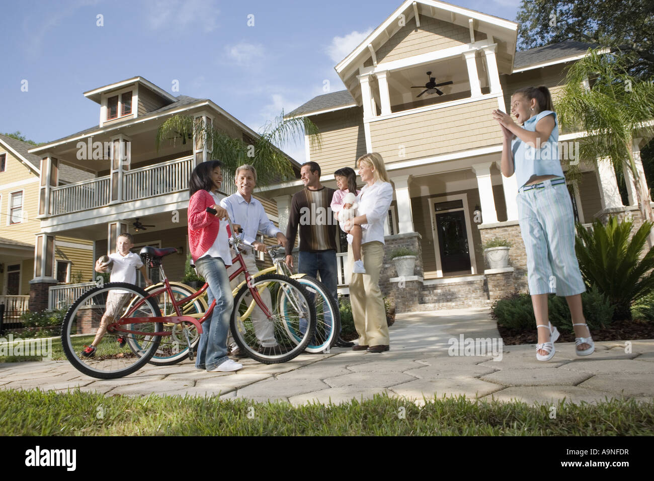 Family with young children conversing with neighbors in front of house ...