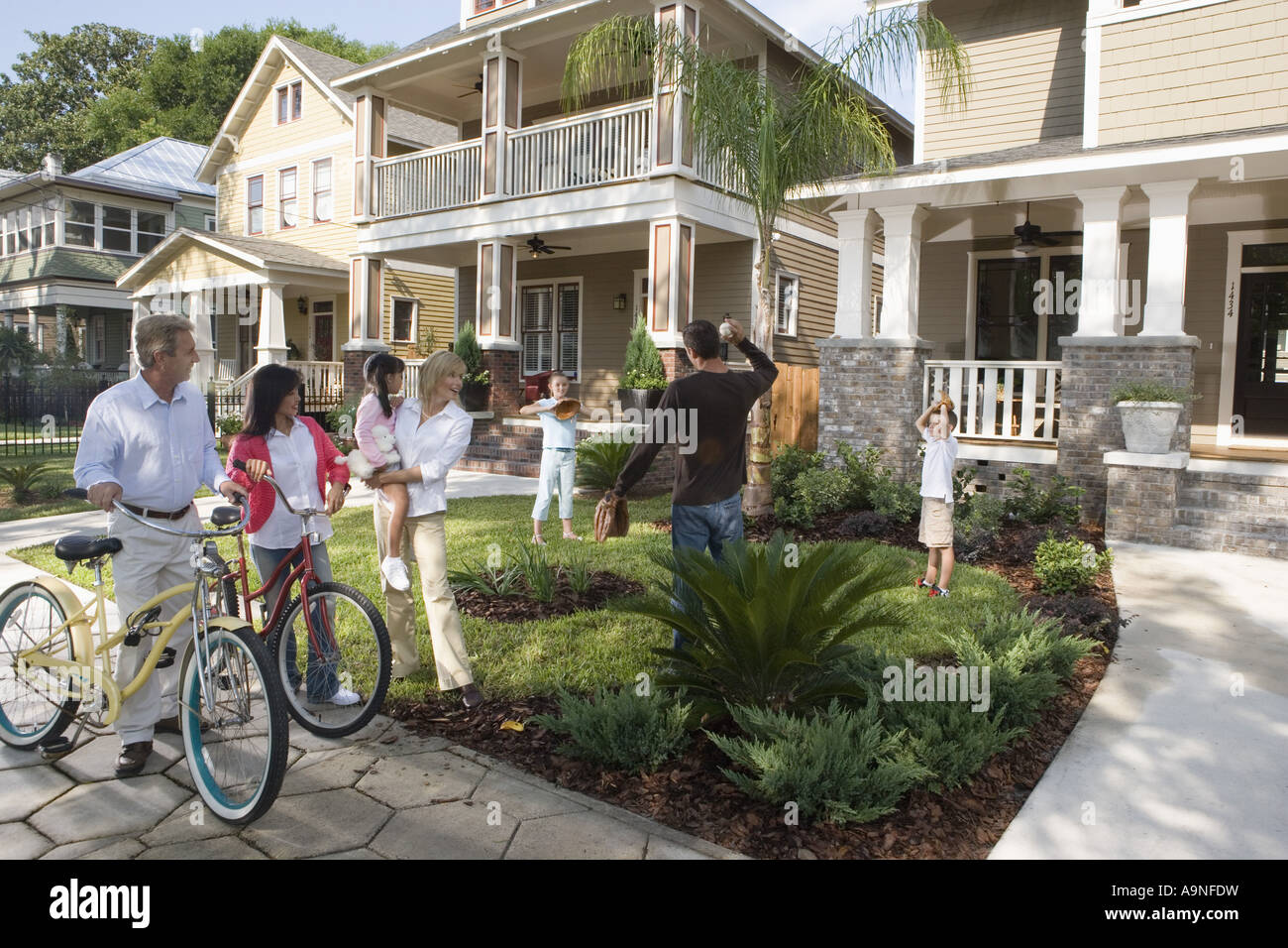 Family with young children conversing with neighbors in front of house ...