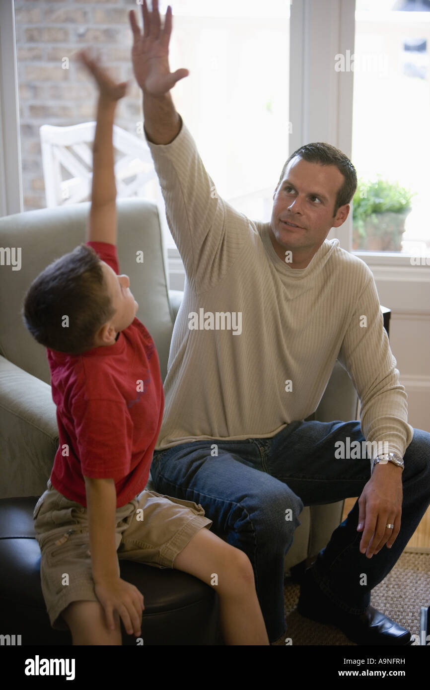 Father high-fiving his son in living room Stock Photo - Alamy