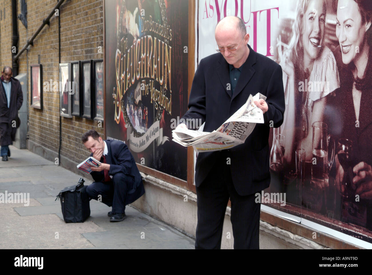 TWO PEOPLE READING IN THE STREET Stock Photo - Alamy