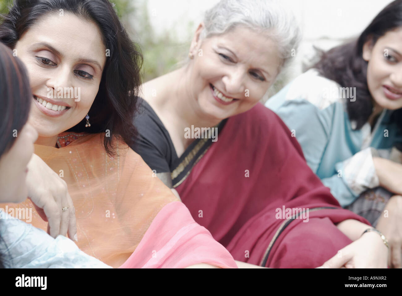 Four women sitting together smiling Stock Photo - Alamy