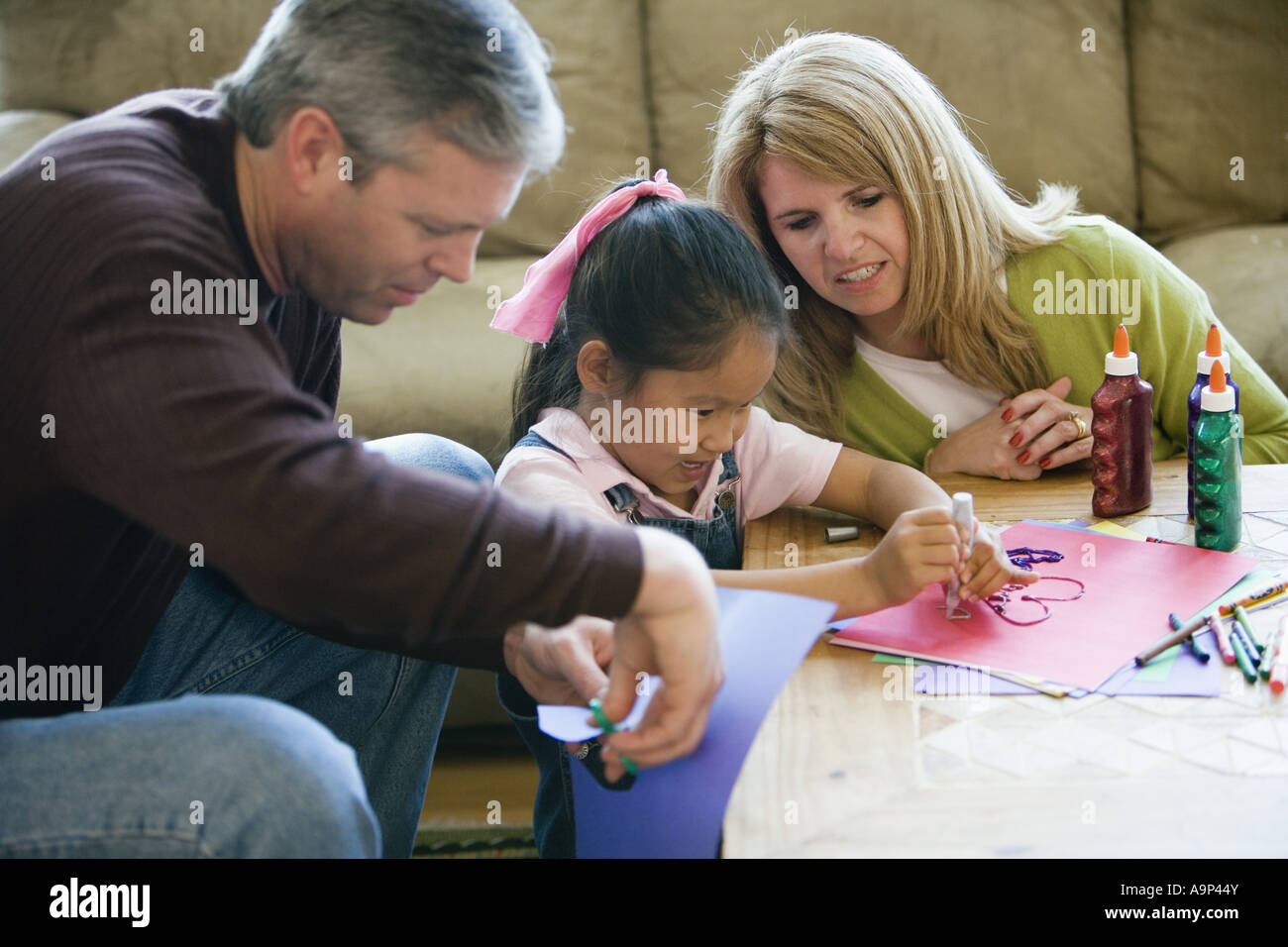 Parents helping their daughter with art work Stock Photo - Alamy