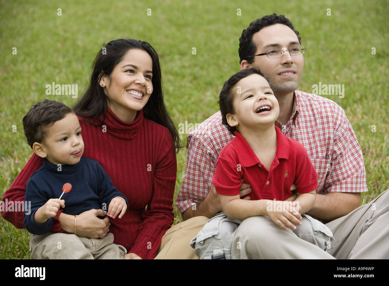 Hispanic family sitting on grass Stock Photo - Alamy