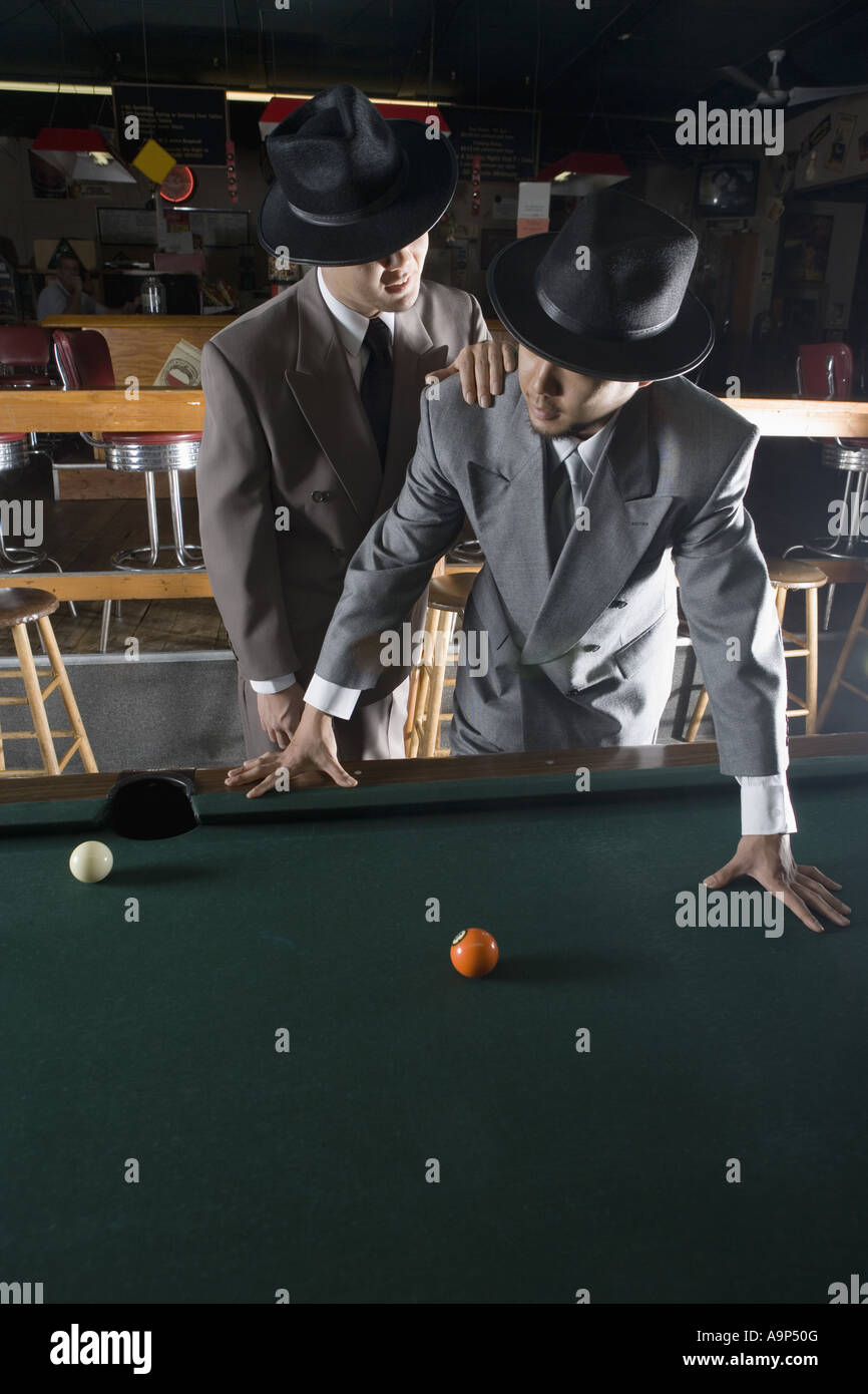 View of two men in suits and hats standing beside billiards table and ...