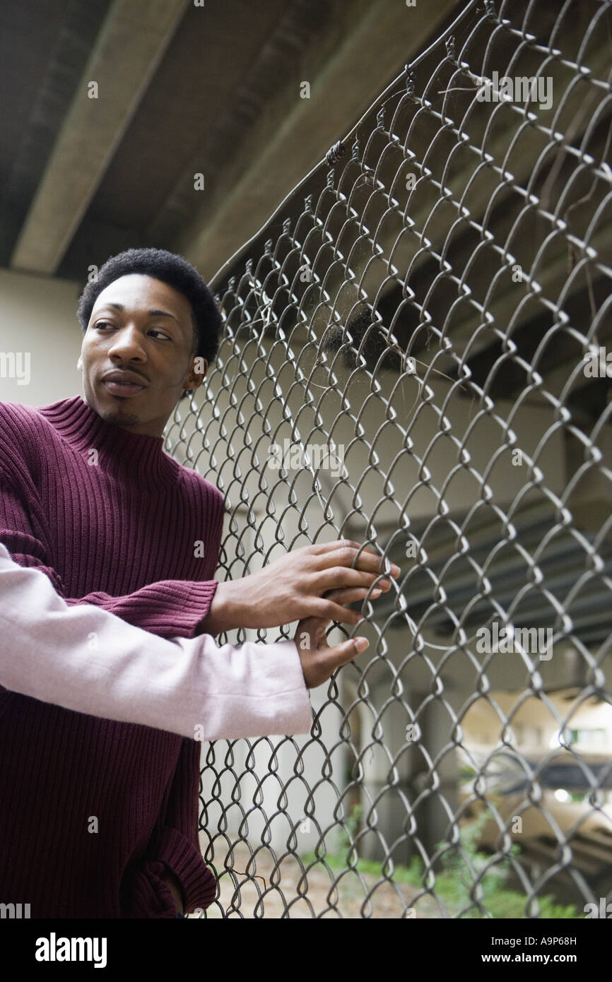 Young man on chain link fence hi-res stock photography and images - Alamy