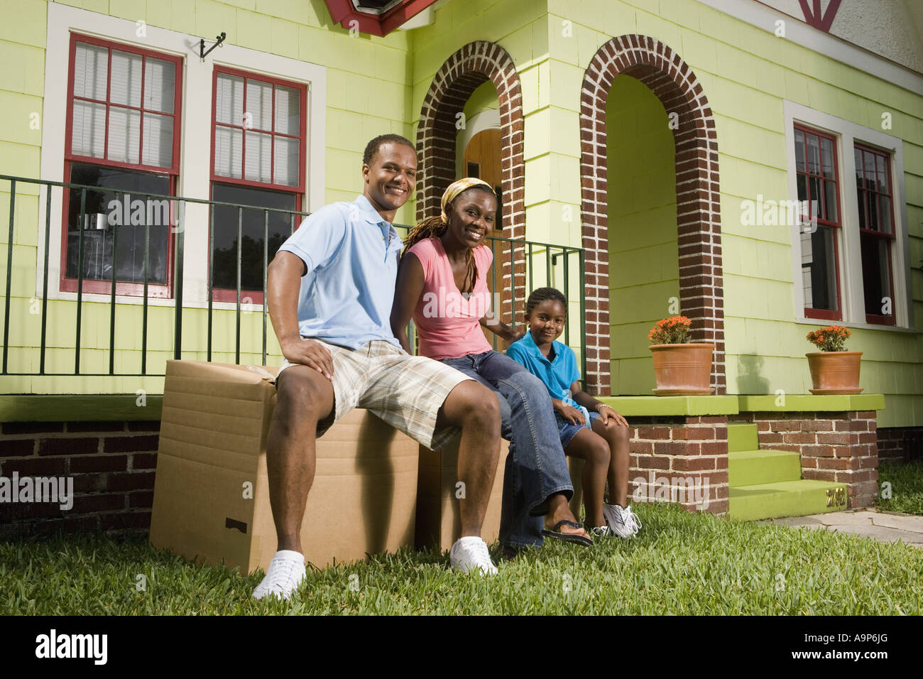 Portrait of a family sitting on boxes outside house Stock Photo - Alamy