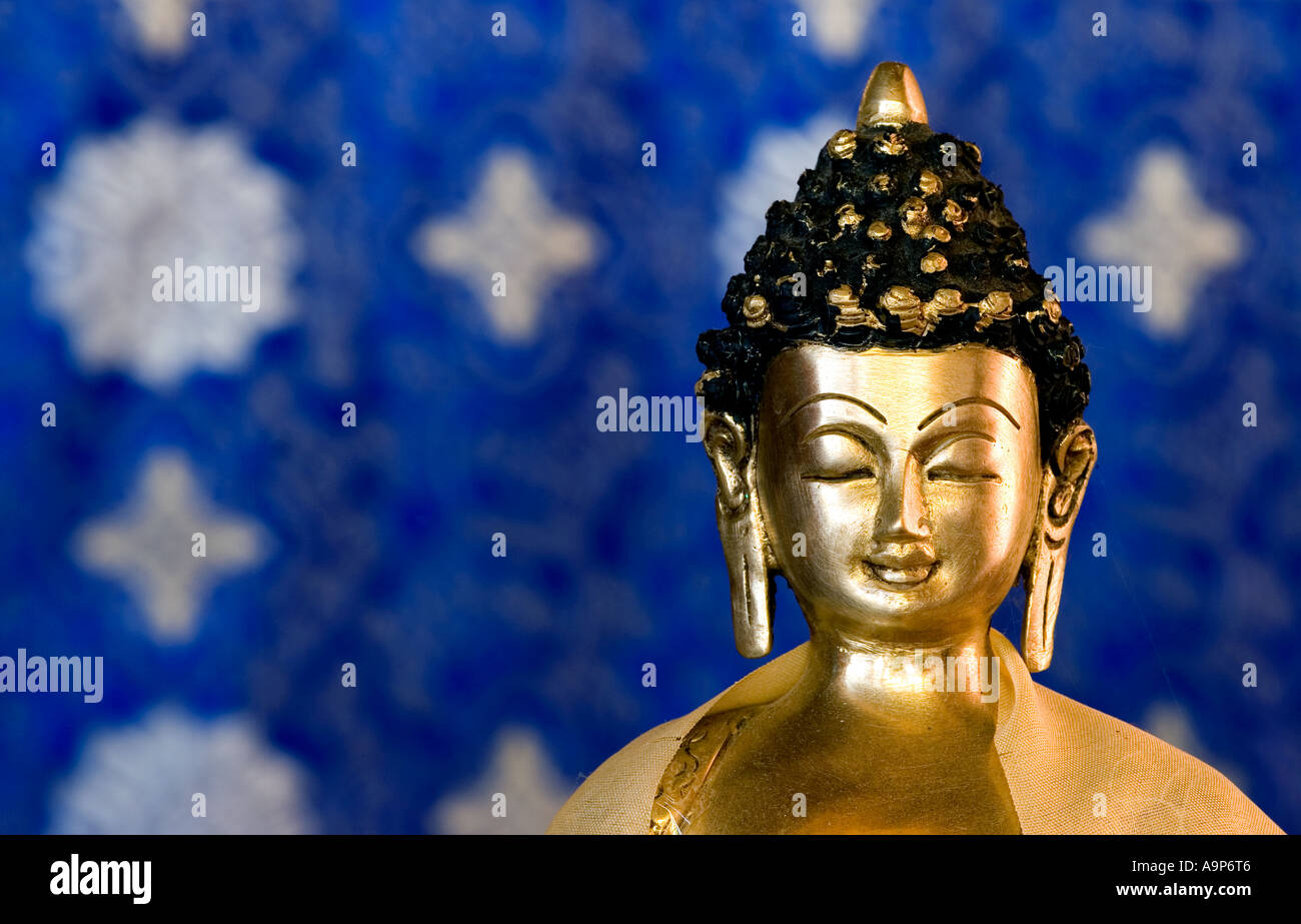 Buddha face statue against a blue cloth background Stock Photo - Alamy