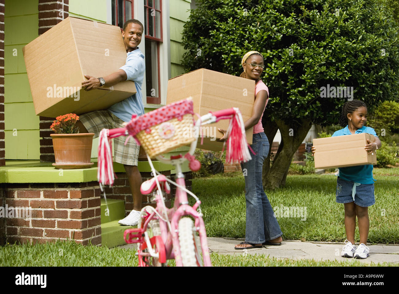 Family moving boxes into house Stock Photo - Alamy