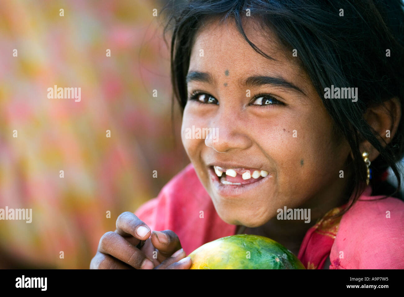 Happy lower caste Indian street girl, smiling, holding papaya fruit ...