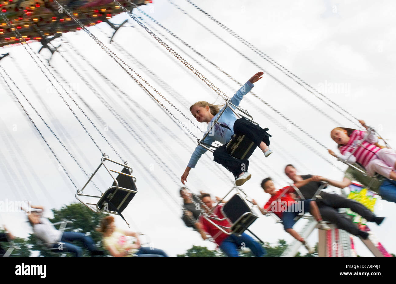 Children enjoying fairground ride swing Stock Photo - Alamy