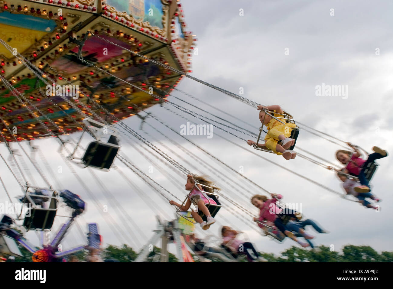 Children enjoying fairground ride swing Stock Photo - Alamy