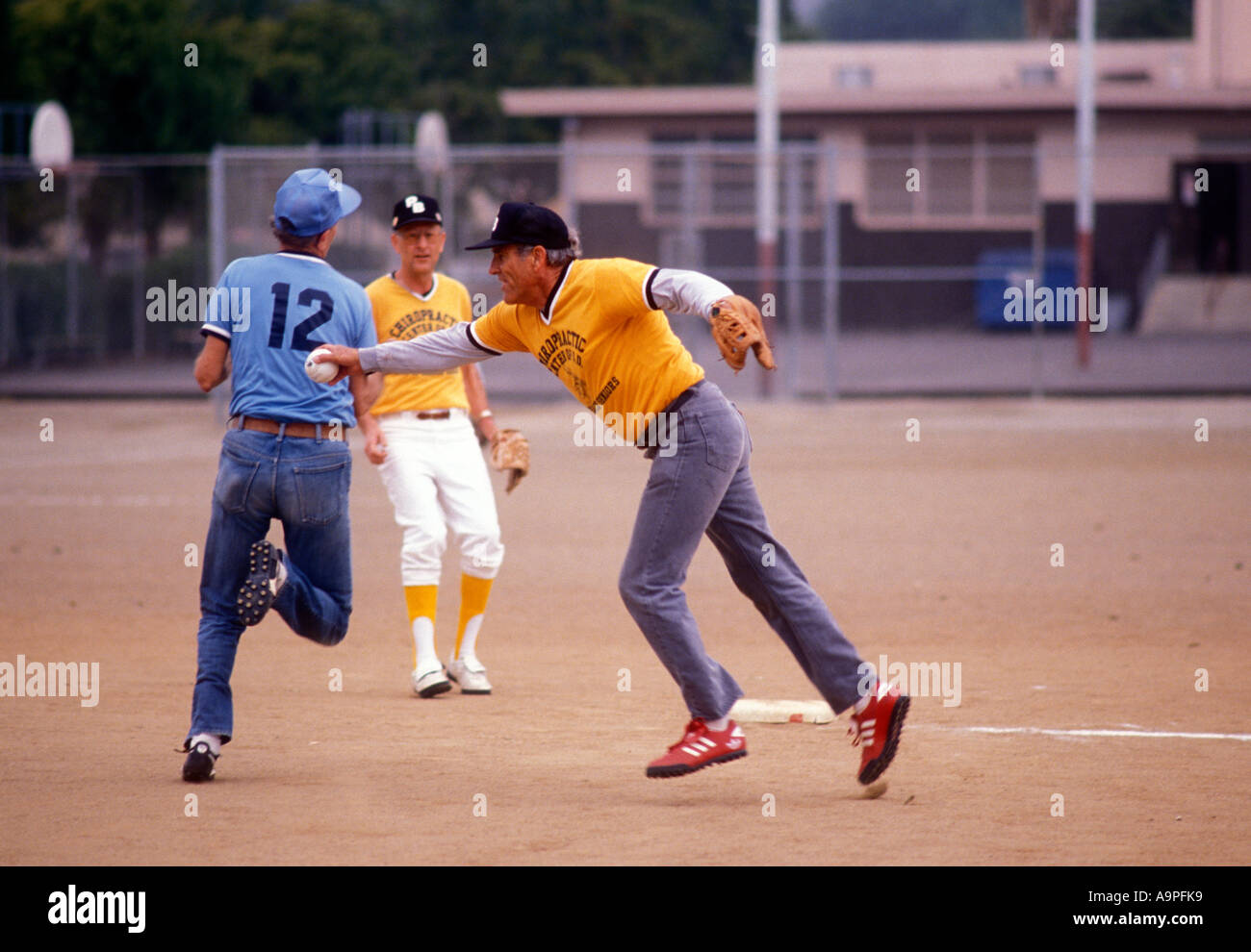 Softball player tagging base runner during game Stock Photo - Alamy