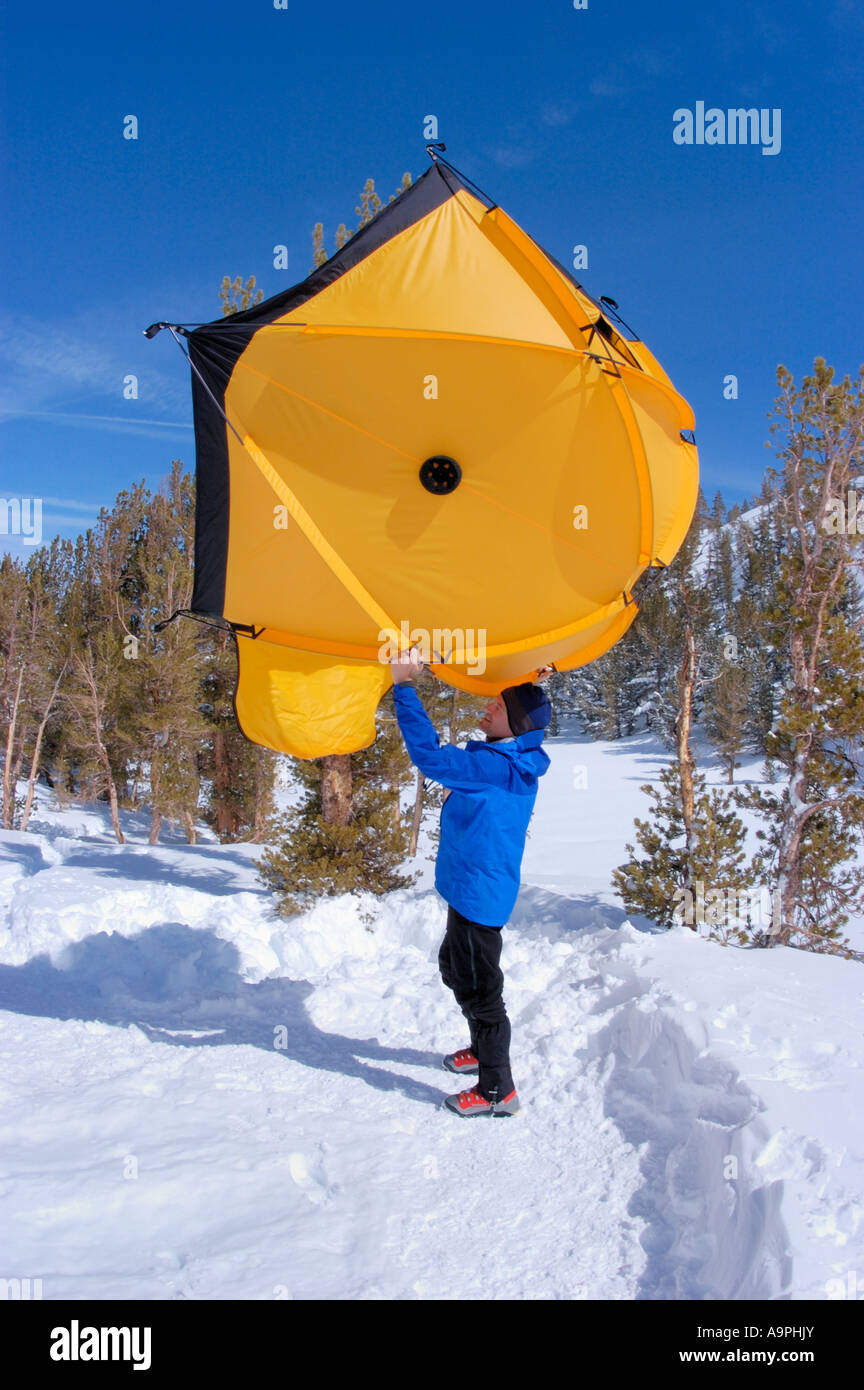 Backcountry skier shaking out a Yellow dome tent Little Lakes Valley ...