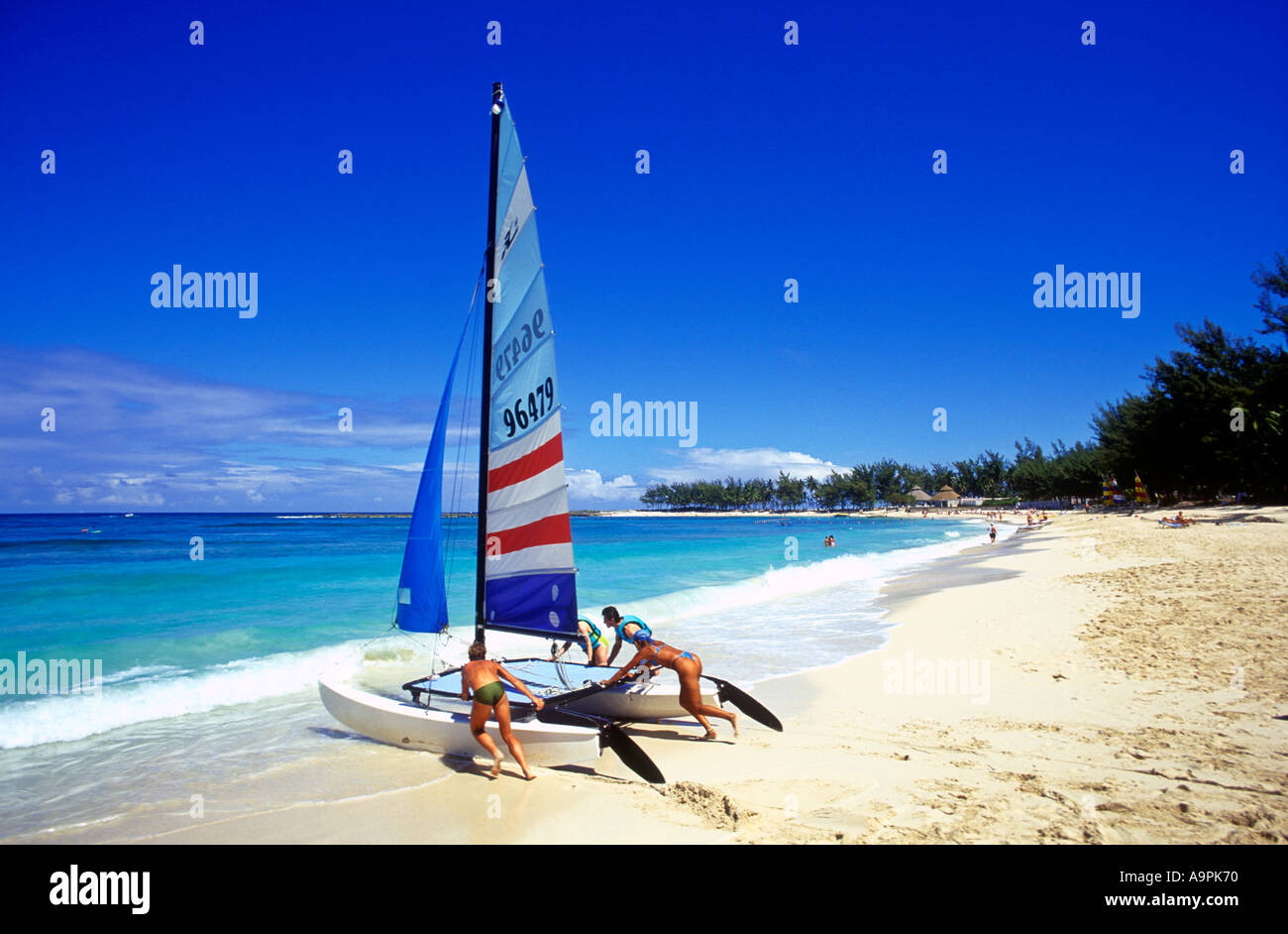 Bahamas Nassau beach scene group of four people pushing a catamaran ...