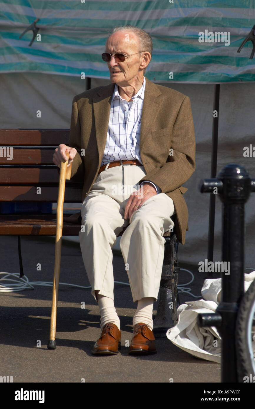 Old Man With Walking Stick Sitting On Bench At St Ives May Bank Stock