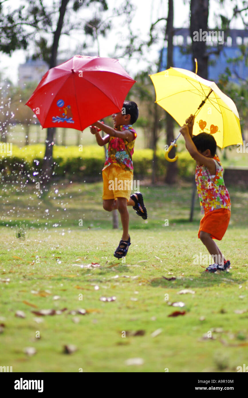 Two kids playing with umbrellas Stock Photo - Alamy