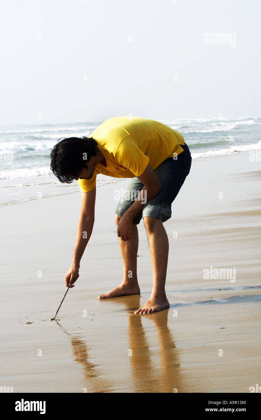 A man drawing on wet beach sand Stock Photo - Alamy