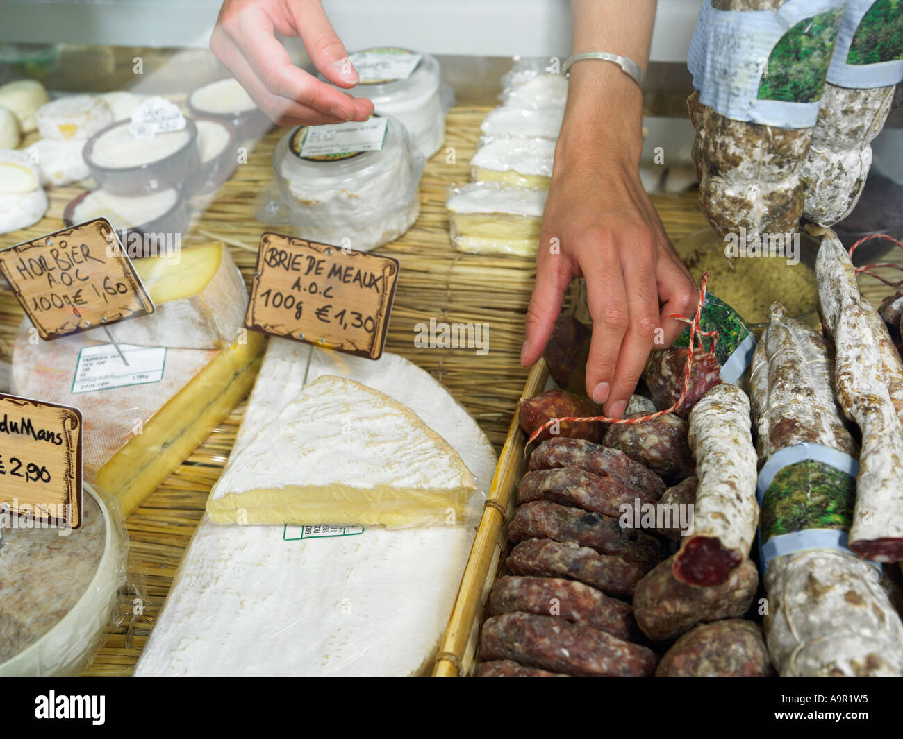 Woman reaching into delicatessen display Stock Photo - Alamy