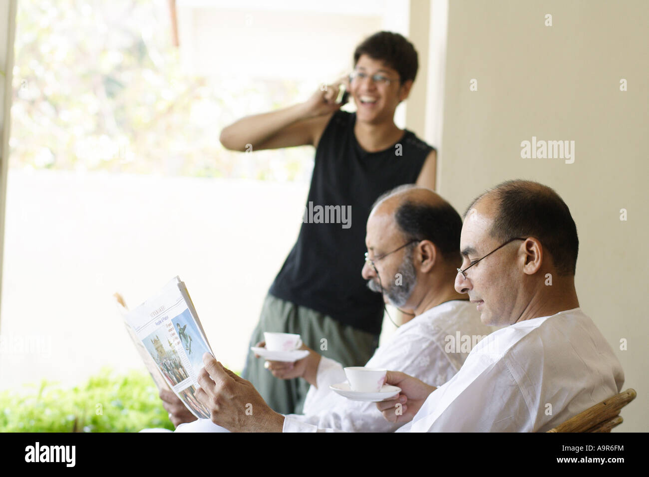 Two men reading newspapers with a young boy standing beside Stock Photo ...