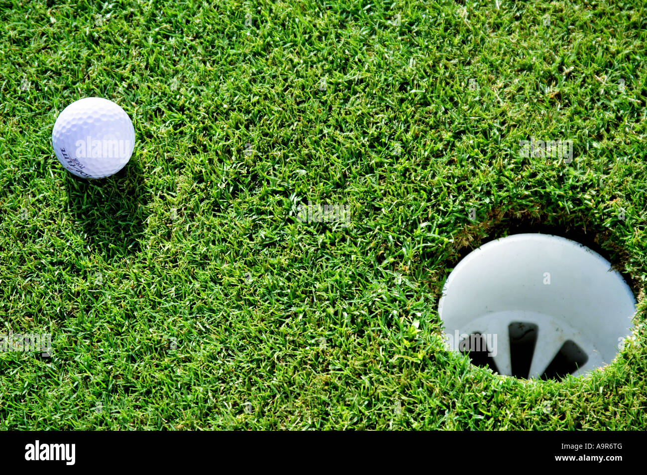 Golf ball next to hole Stock Photo - Alamy
