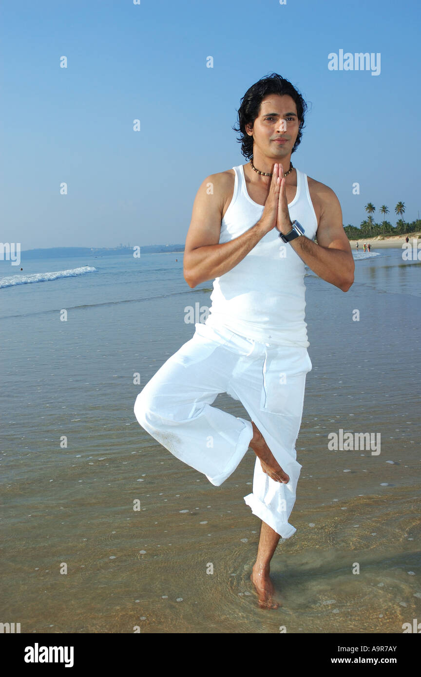 A young man doing yoga at a beach Stock Photo - Alamy