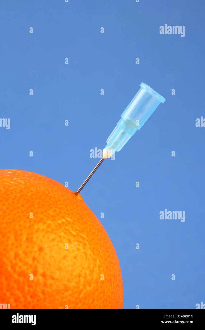 Syringe injecting an orange Stock Photo - Alamy