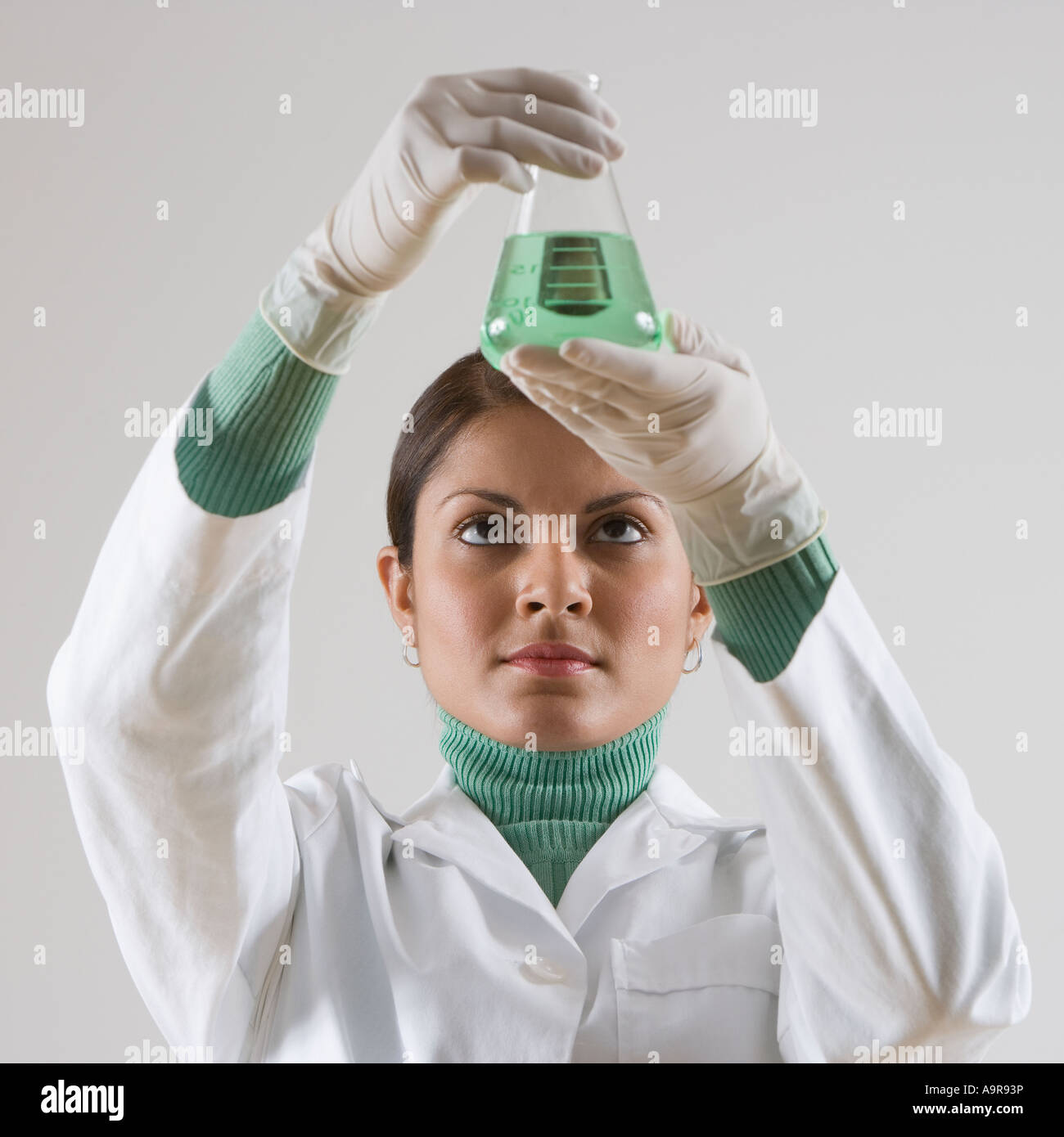Indian female scientist looking at beaker of liquid Stock Photo - Alamy