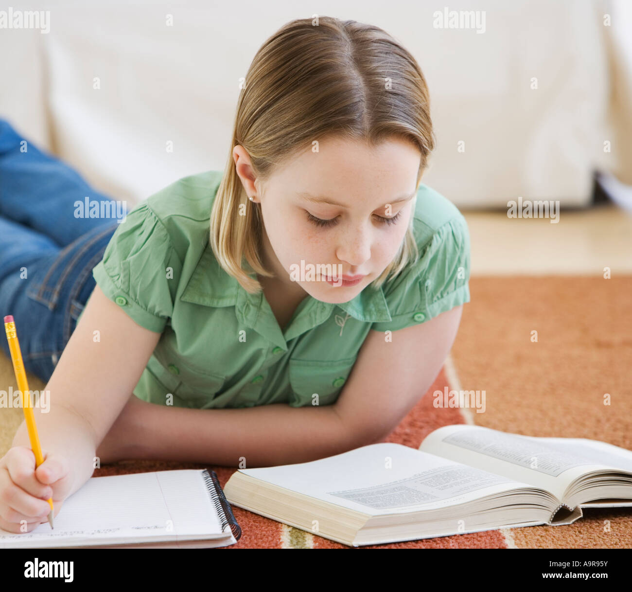 Girl doing homework on floor Stock Photo - Alamy