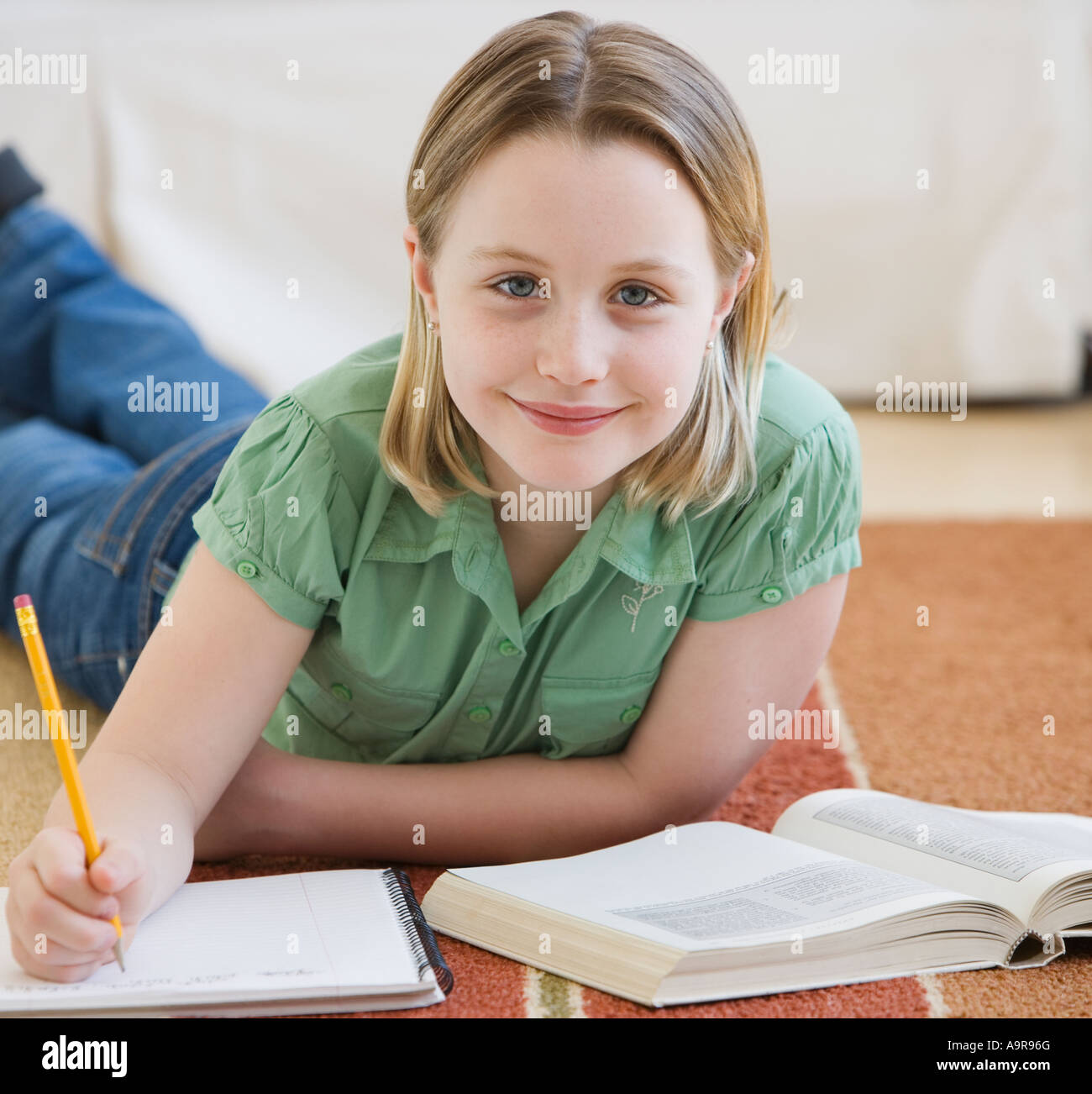 Girl doing homework on floor Stock Photo - Alamy