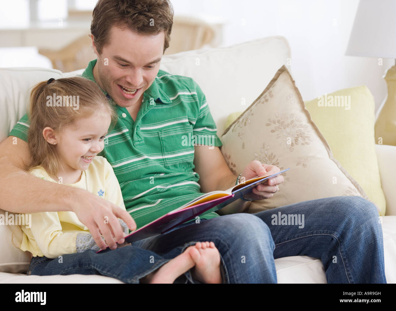 Father reading to daughter on sofa Stock Photo - Alamy