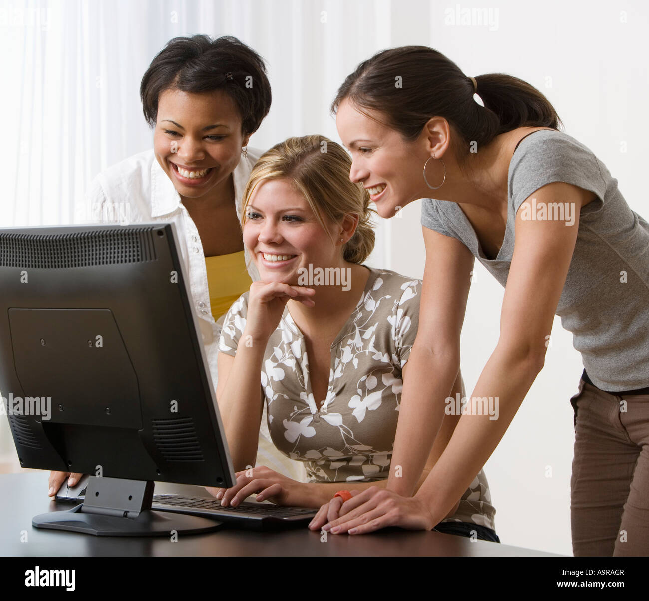 Multi ethnic women looking at computer Stock Photo - Alamy