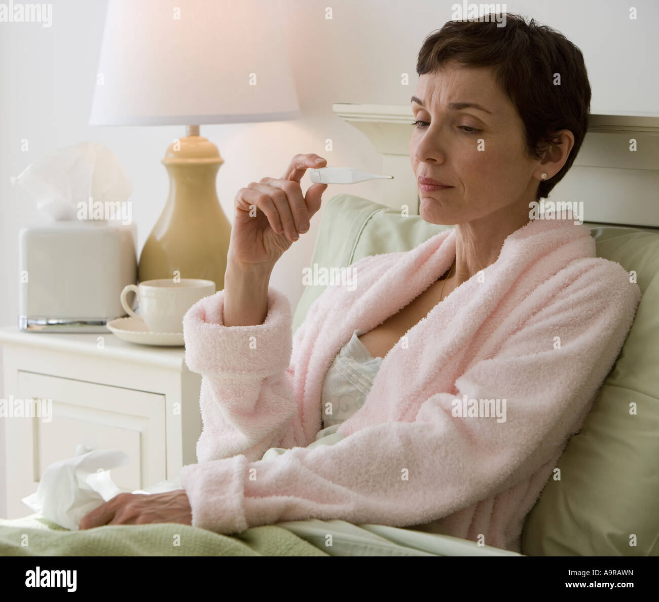 Woman taking own temperature in bed Stock Photo - Alamy