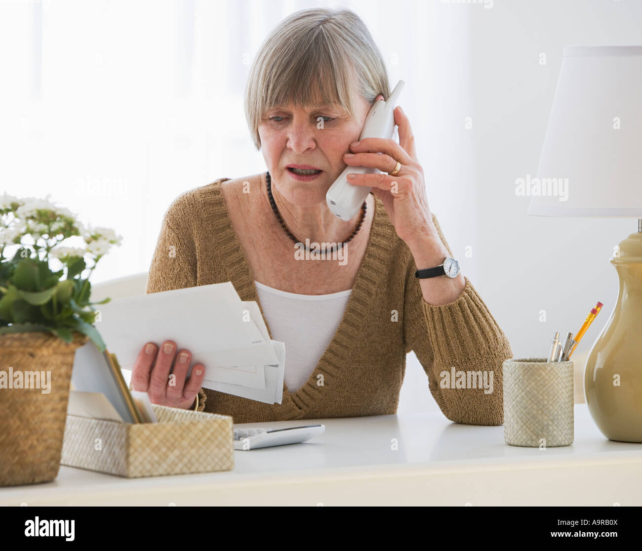 Senior woman looking at bills Stock Photo - Alamy