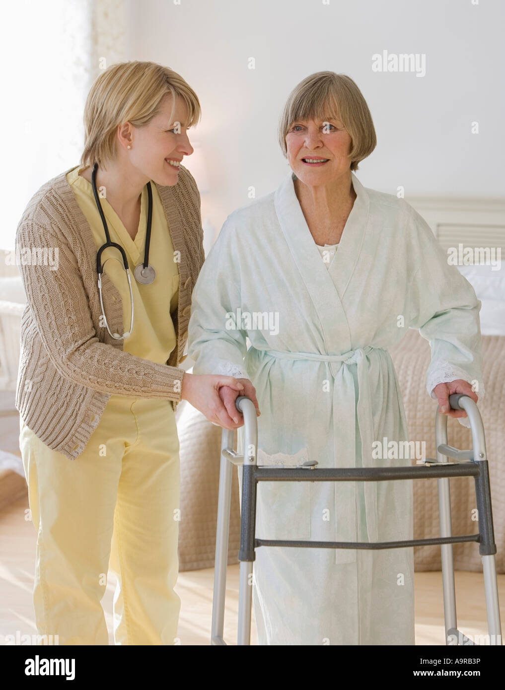 Nurse helping senior woman use walker Stock Photo - Alamy