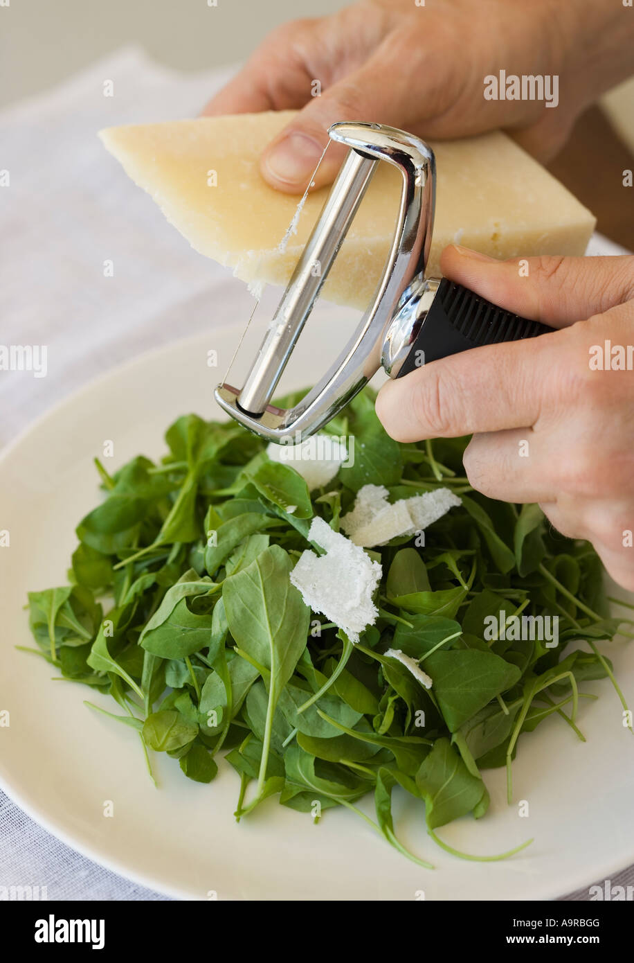 Man shaving cheese onto salad Stock Photo - Alamy