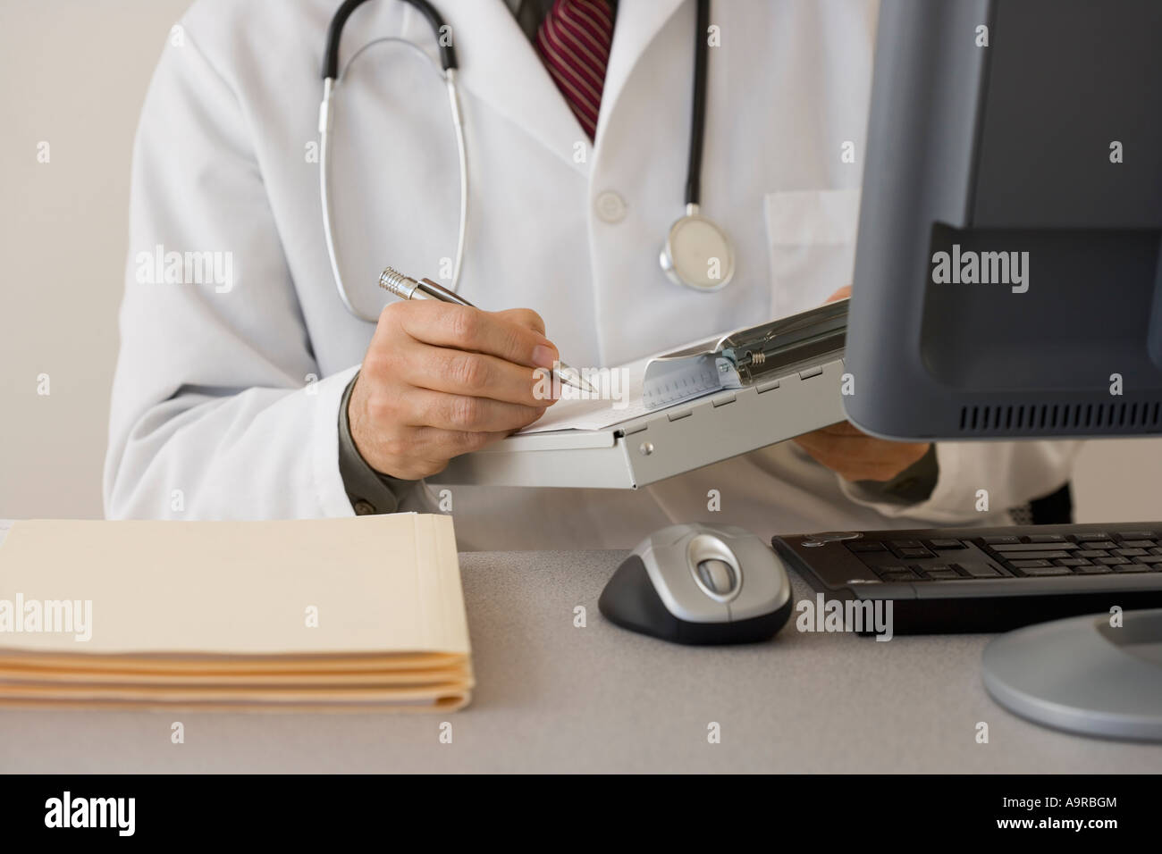 Doctor writing on chart at desk Stock Photo - Alamy