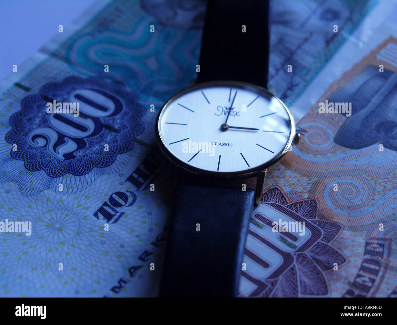 wrist watch on banknotes in a dark setting illustrating erning money ...