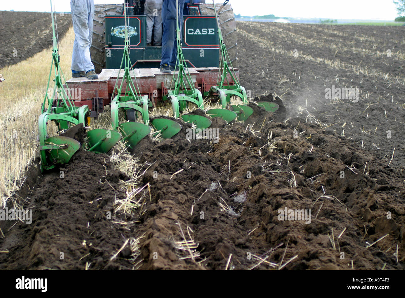 Horizontal Antique tractor pulling a five furrow plough Stock Photo - Alamy
