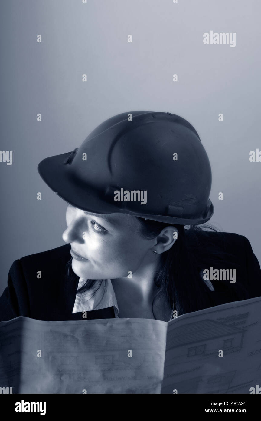 A young female architect in suit inside new build with house plans ...