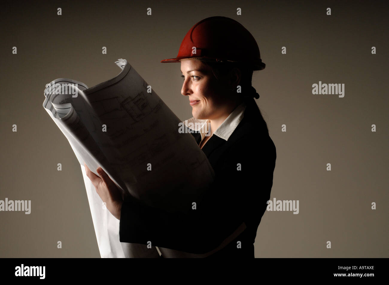 A young female architect in suit inside new build with house plans ...