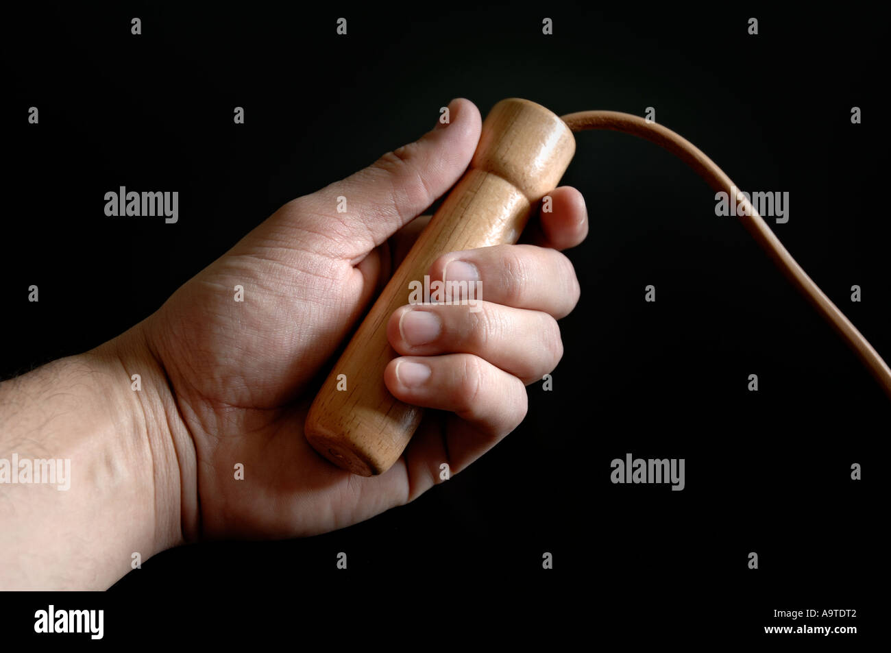 Man holding handle of leather jumping rope over black background Stock ...