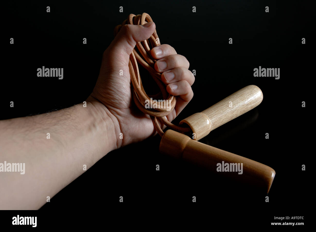 Man holding leather jumping rope over black background Stock Photo - Alamy
