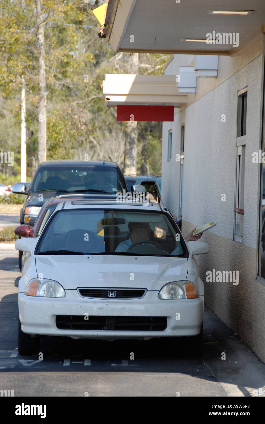 Cars use a drive through window to order and pick up fast food at a ...