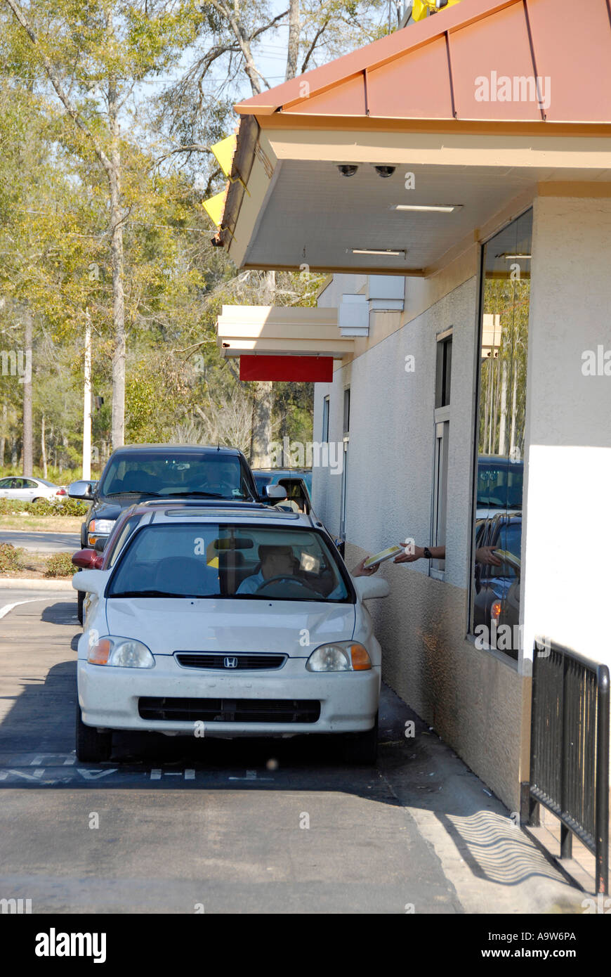 Cars use a drive through window to order and pick up fast food at a ...