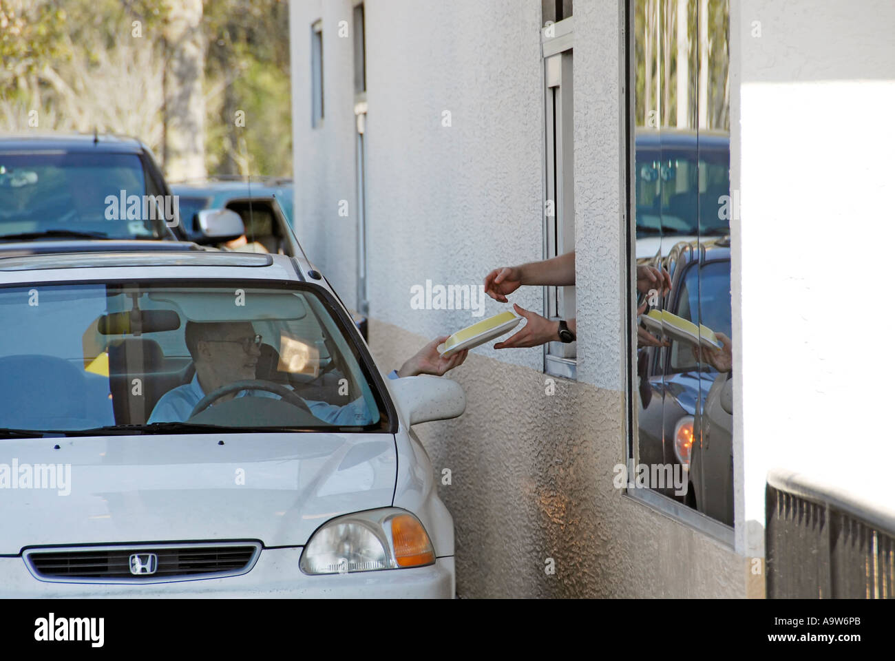 Cars use a drive through window to order and pick up fast food at a ...