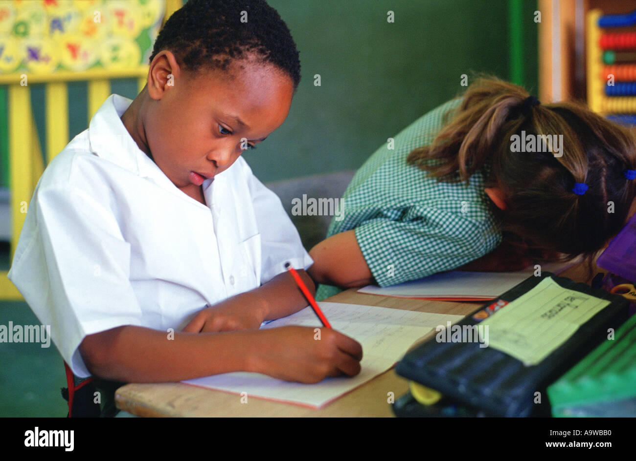 Multicultural children writing in classroom Johannesburg Gauteng South ...