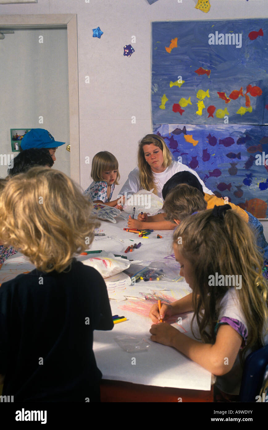 GROUP OF CHILDREN SEATED AROUND TABLE WITH TEACHER IN KINDERGARTEN ...