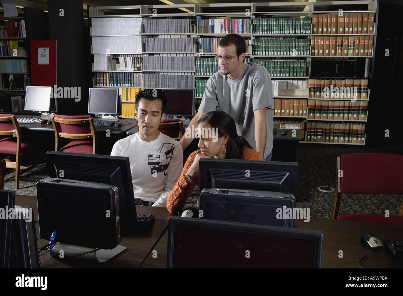 Three university students using computers in the library Stock Photo ...