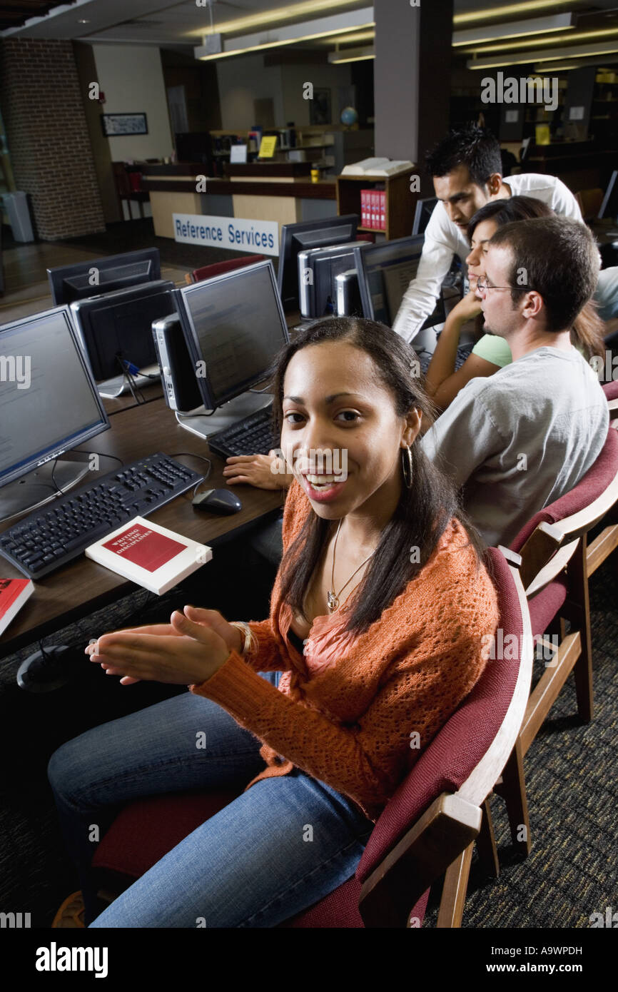 Portrait of a smiling woman sitting with friends while using computers ...