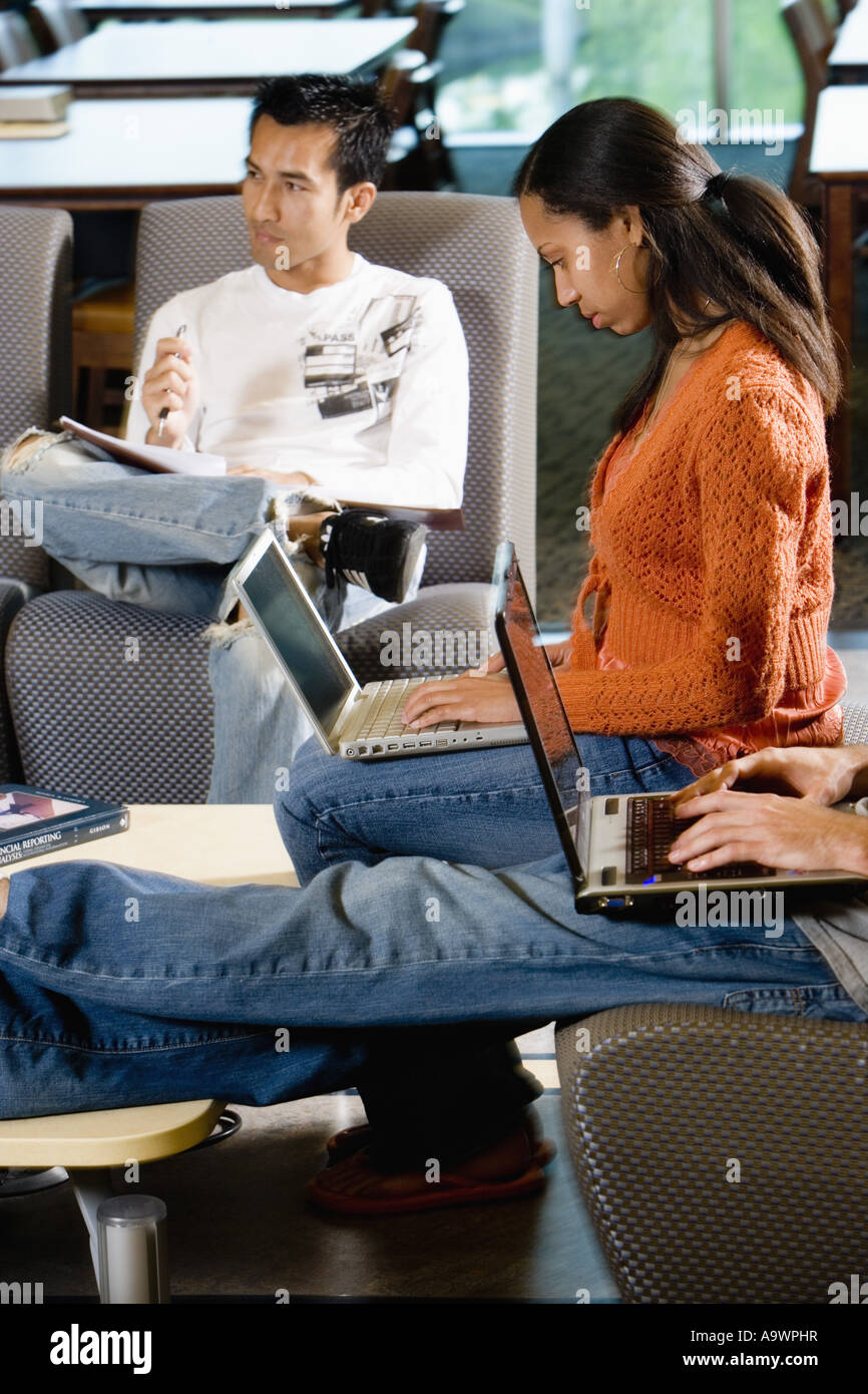 Students with laptop computers in library sitting on sofas studying ...